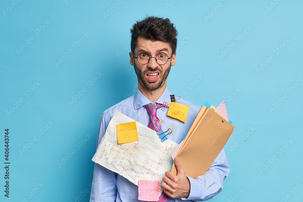 Displeased unshaven businessman looks with aversion at camera frowns ...