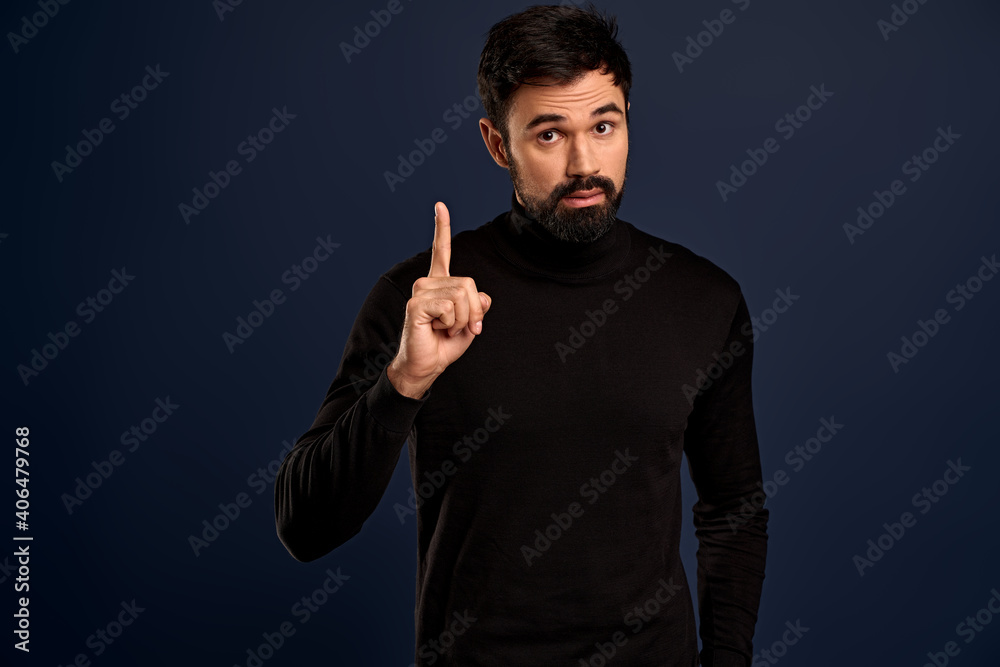 Handsome bearded man in black high neck sweater raise one finger and ...