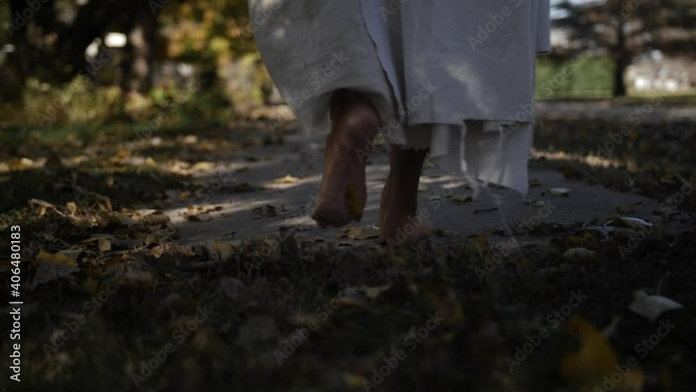 A dramatic slow motion closeup of Jesus' feet walking down a sidewalk ...