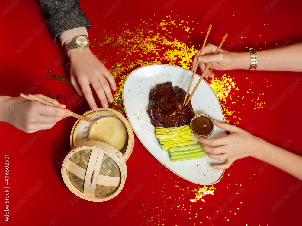 Chinese national dish Peking duck. Male and female hands reaching for ...