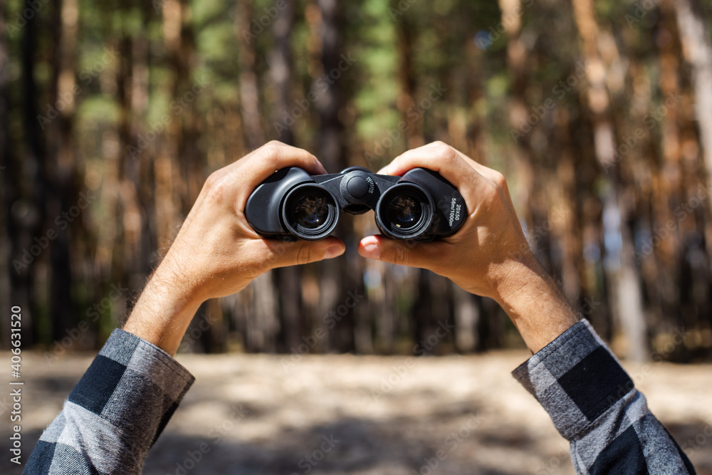 Man looks through binoculars against the background of the forest ...