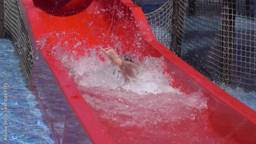 Boy slide on slider in water park on summer holiday. Happy boy sliding ...