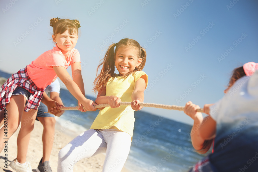 Cute children pulling rope during tug of war game on beach. Summer camp ...