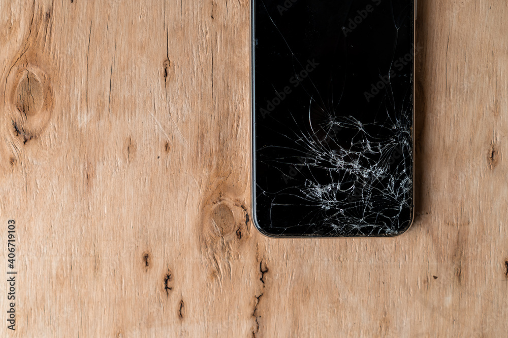 Closeup of black smartphone with broken back glass on white background ...