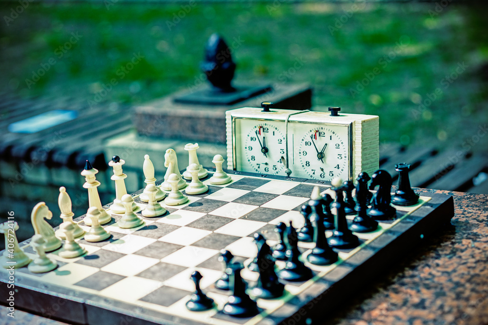 Chess board with pieces and clock on wooden desk In connection with the ...