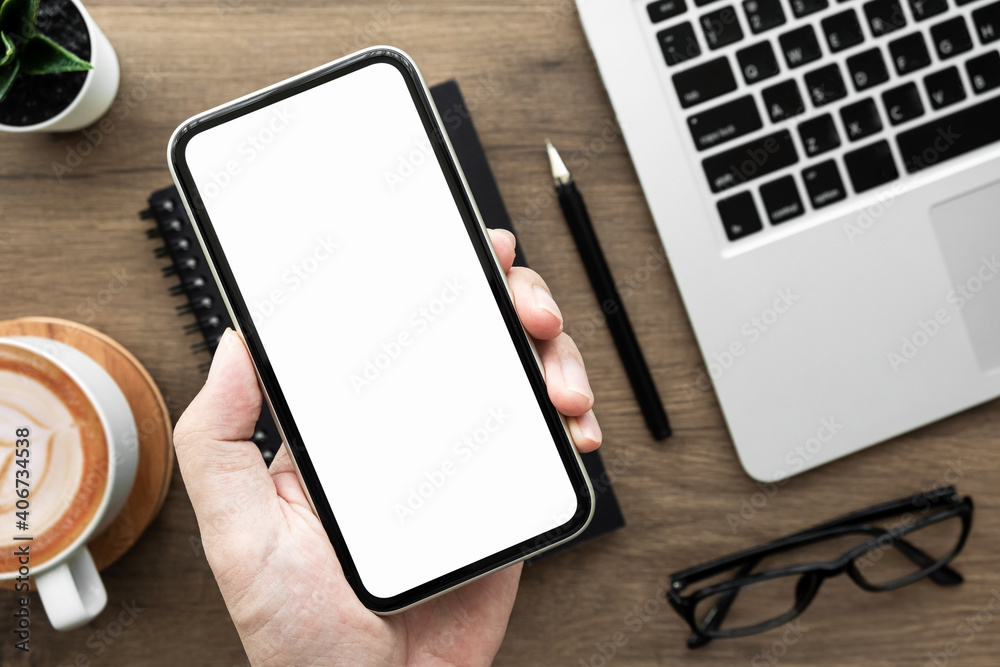 Hand holding smartphone with white blank mock up screen over wood ...