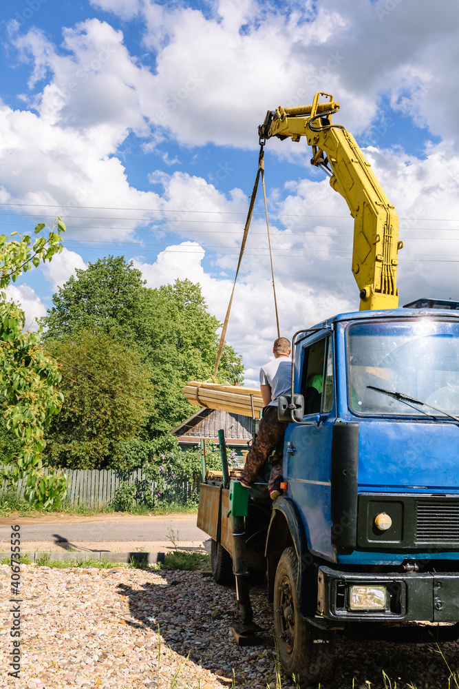 A blue cargo loader with a manipulator unloads the delivered building ...