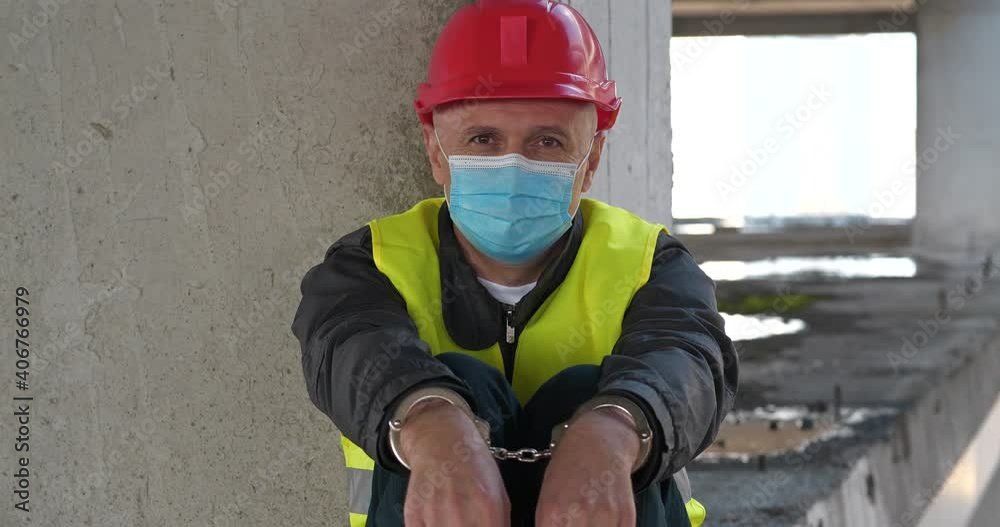 Handcuffed workman in blue medical protective face mask and red hard ...
