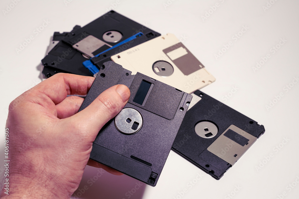 Man showing inside of a floppy disk on scattered floppy disks. Old ... Man showing inside of a floppy disk on scattered floppy disks. Old ...