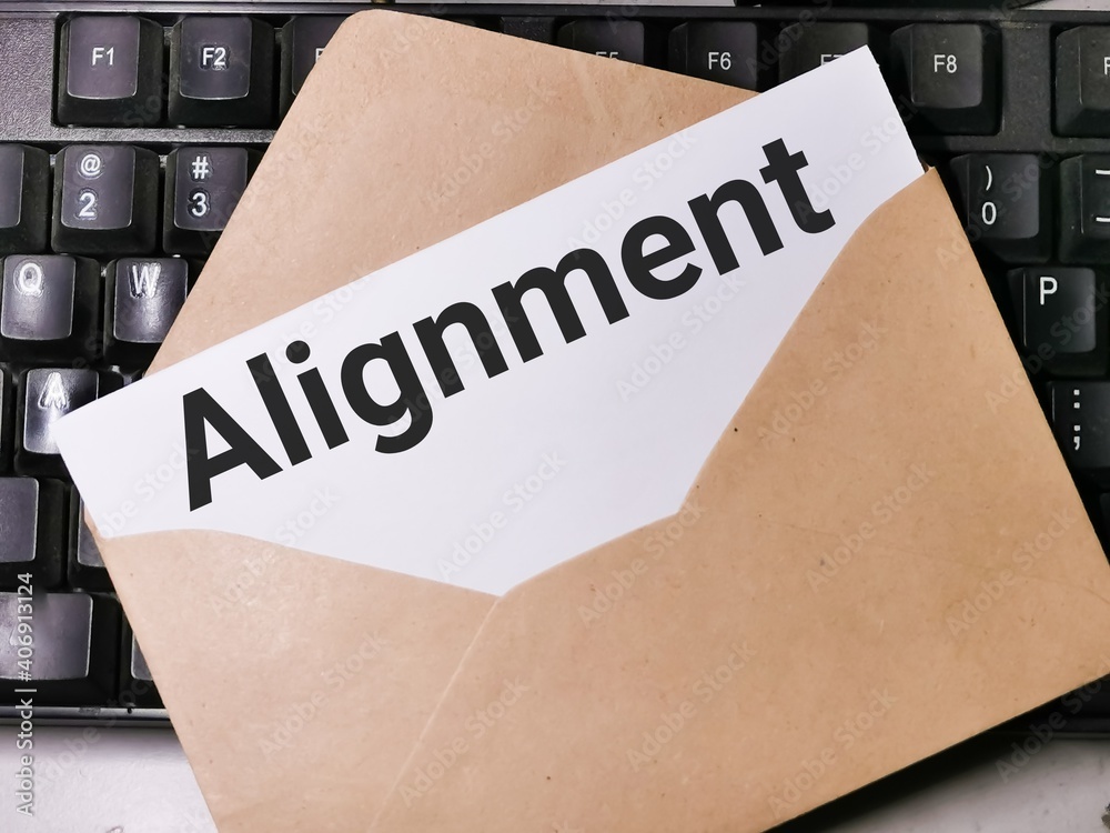 Text ALIGNMENT written on white paper note in the envelope on computer ...