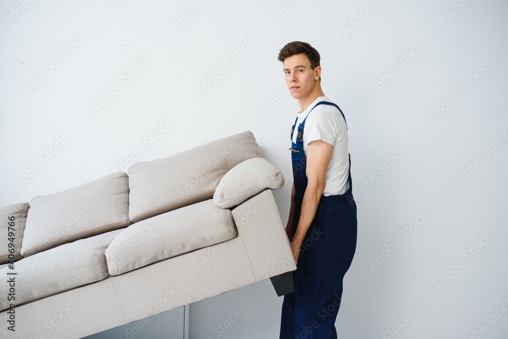 Loader moves sofa, couch. worker in overalls lifts up sofa, white ...