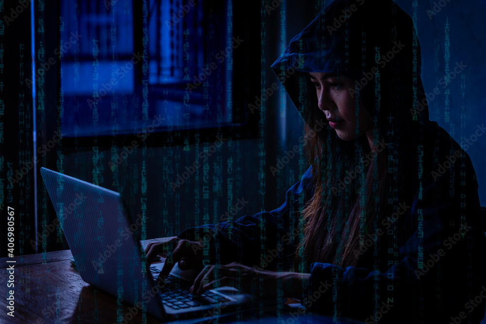 Hackers woman typing laptop computer keyboard In a dark room, wearing a ...
