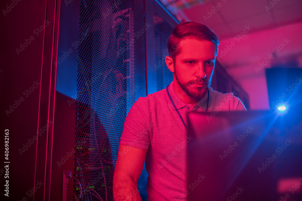 Man near server rack at computer in datacenter Stock Photo | Adobe Stock