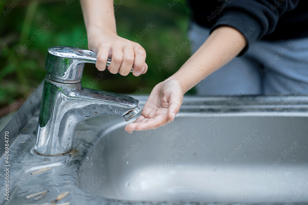 Girl washing her hands at the park. Baby try to turn off water faucet ...