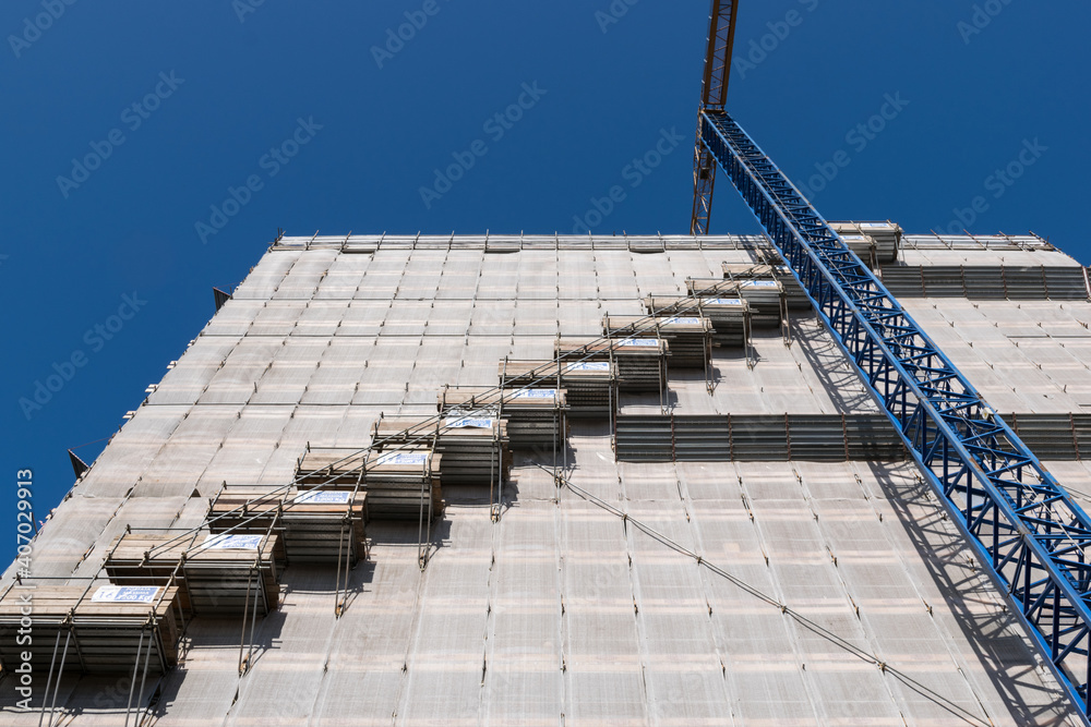 Bottom view of building under construction with façade scaffolding and ...