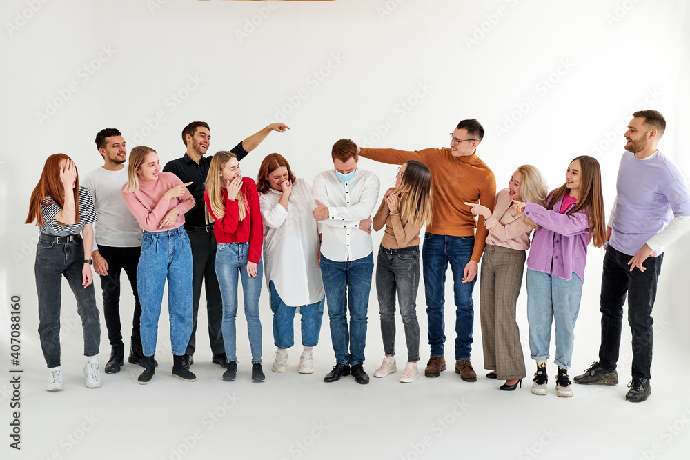 sick male in medical mask stand among healthy people laughing at him ...