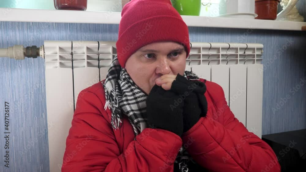 Man freeze at home and sits near central heating system. White metal ...