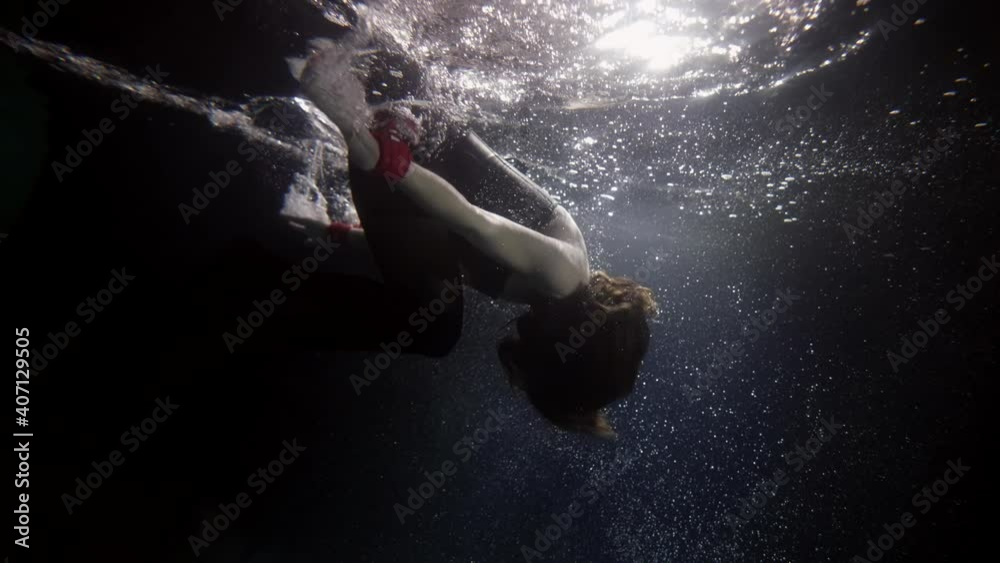 Video Stock A woman in a black suit floats upside down under the water ...