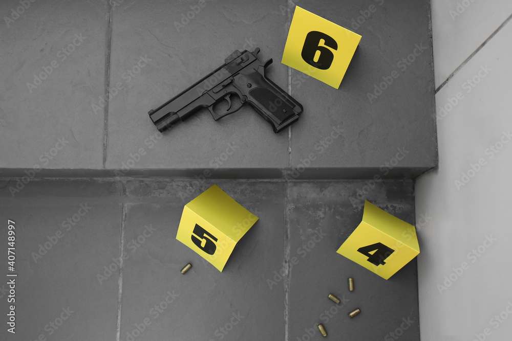Crime scene with gun, bullet shells and evidence markers on stairs ...