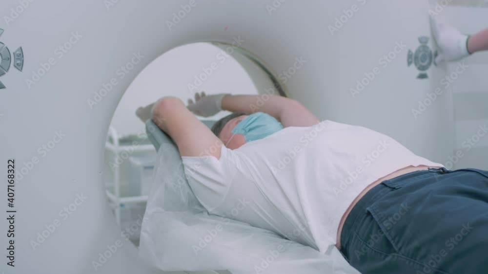 A patient in a protective medical mask lies in a modern computed ...