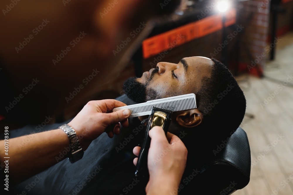 Black man in the barbershop. Cute black man makes a haircut in the ...