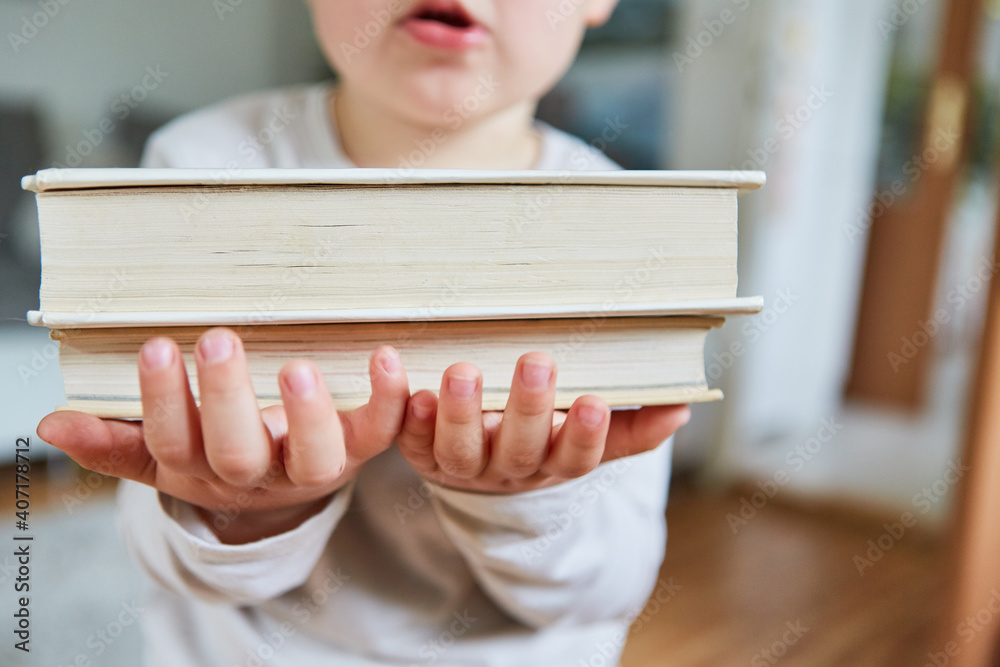 Small child carries books in his hands Stock Photo | Adobe Stock
