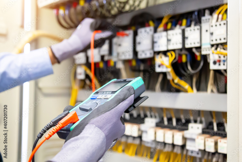 Electrical engineer using digital multi-meter measuring equipment to ...
