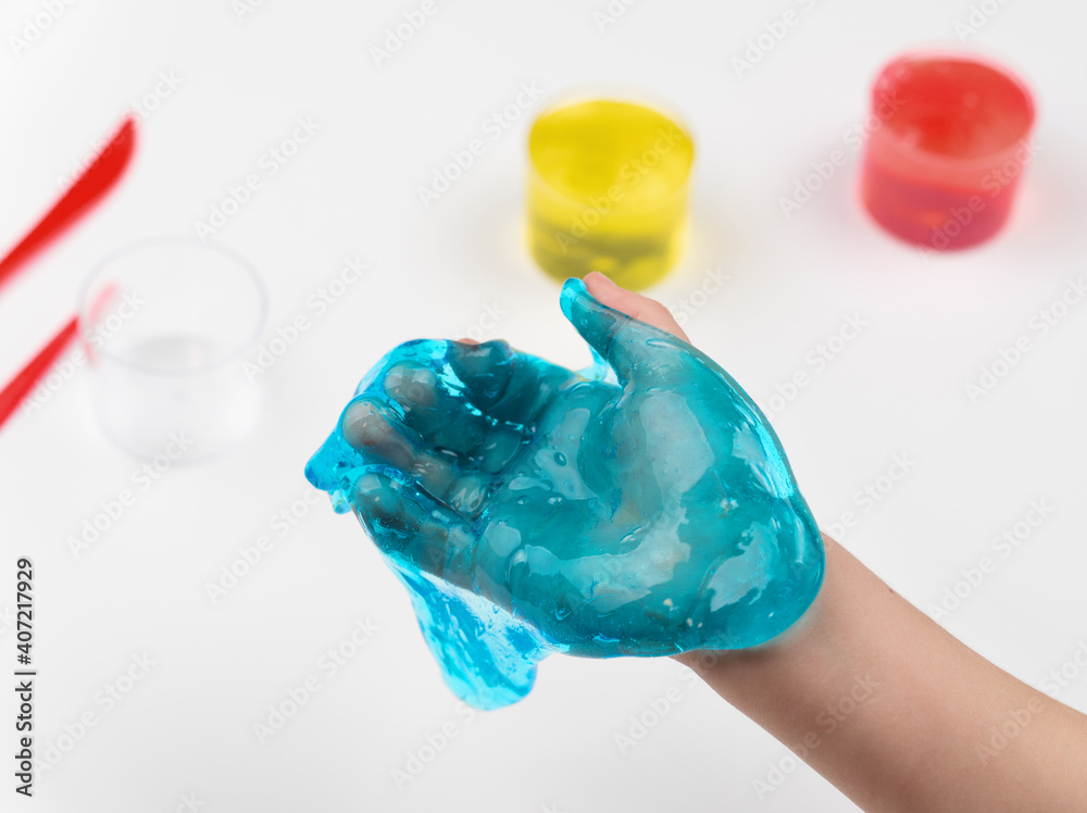 Slime in the hand of a child on a light background. The child plays ...
