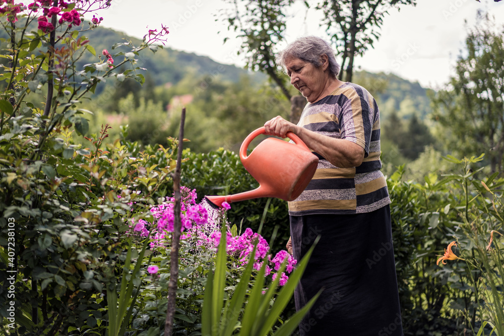 Very old and happy healthy woman in her backyard of house taking care ...
