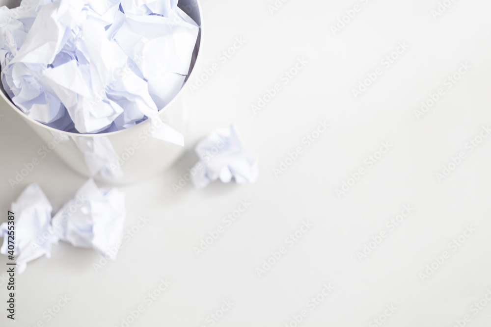 Overfilled white recycle bin on a light background with crumpled ...