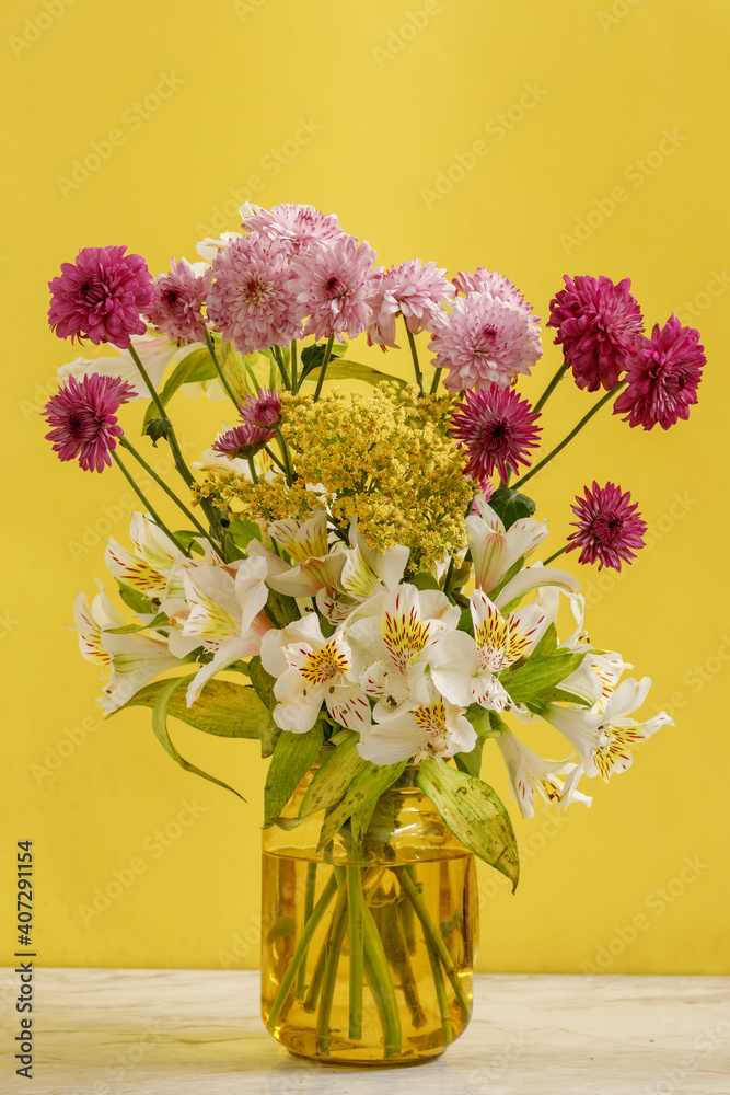 Florero amarillo con flores de diferentes tipos y colores sobre una ...