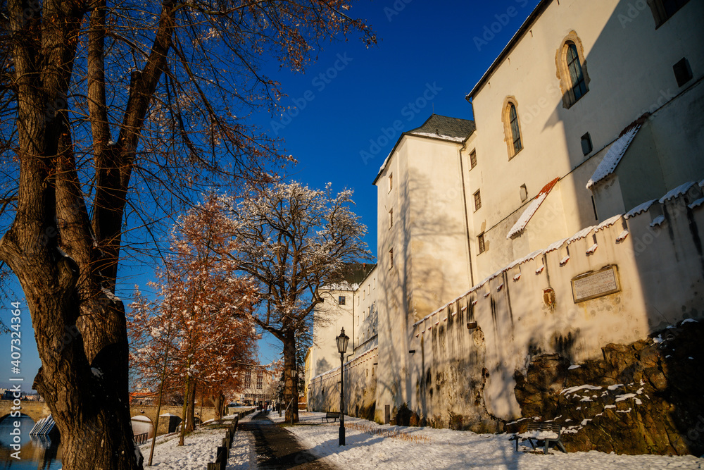 Medieval gothic castle, waterfront buildings over Otava River in winter ...