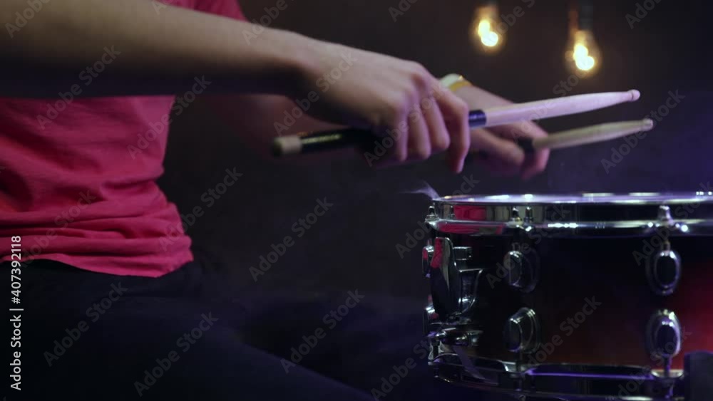 A man plays with sticks on a snare drum in a dark room with a beautiful ...