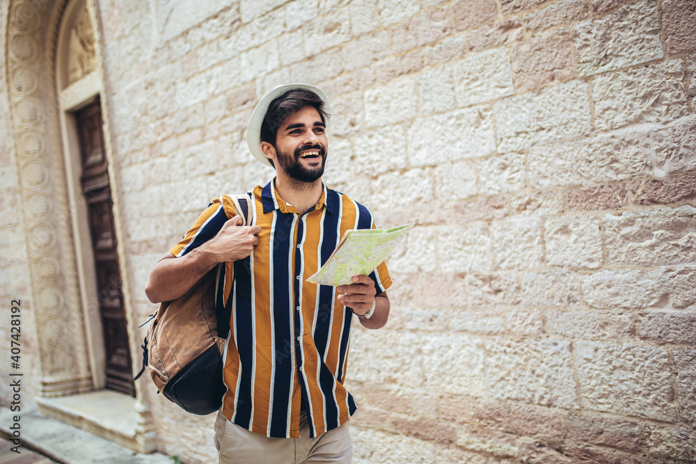 Happy tourist with backpack is making travel across city uses a map for ...