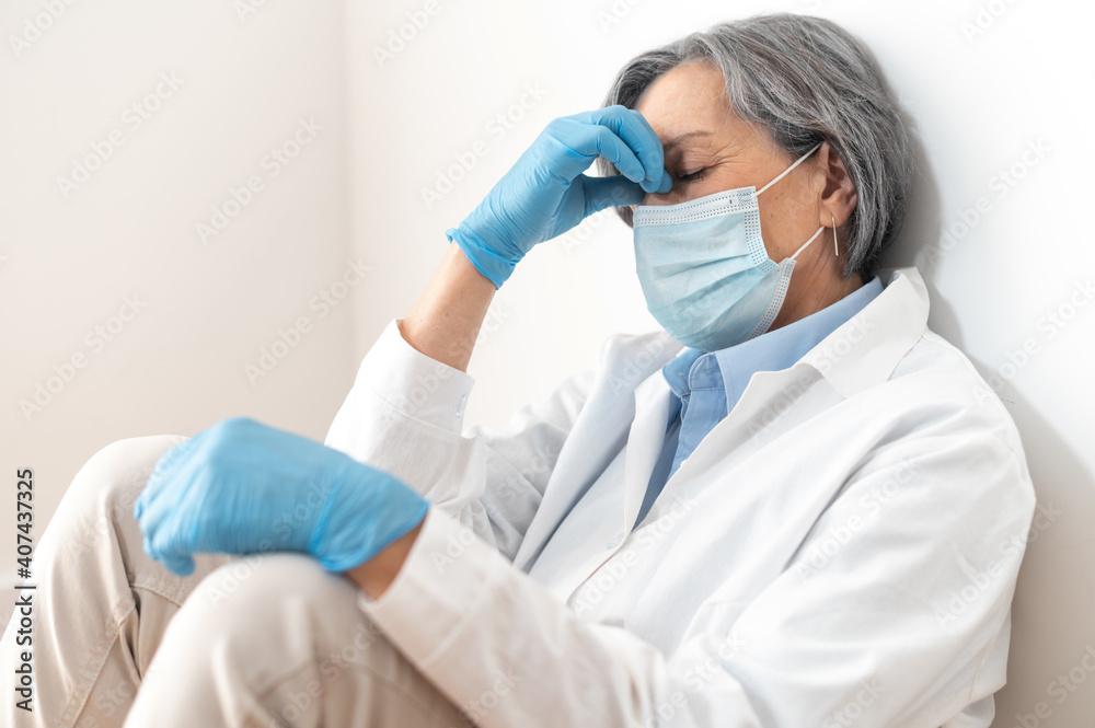 Stressed and tired sad female doctor in uniform, face mask and gloves ...