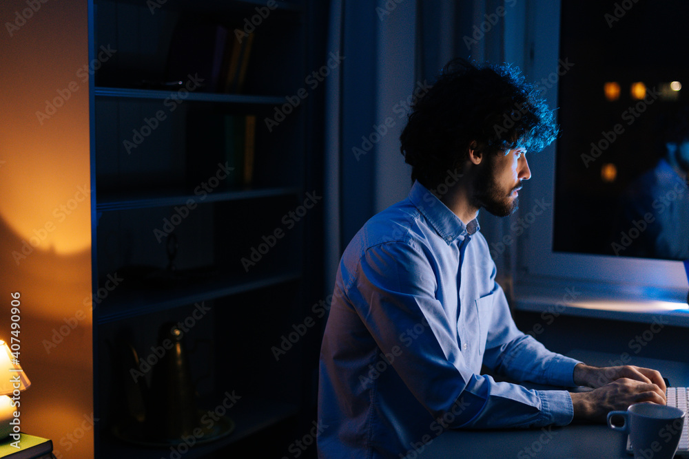Side view of serious young business man working on computer in home at ...