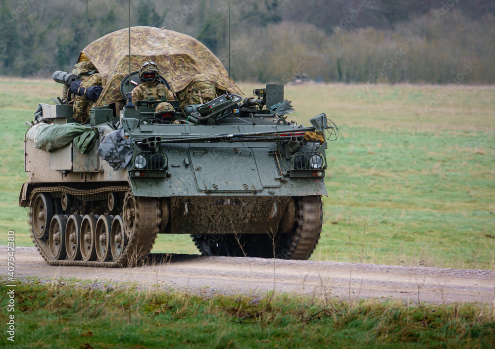 british army FV430 in motion, fully loaded with troop bergens under a ...