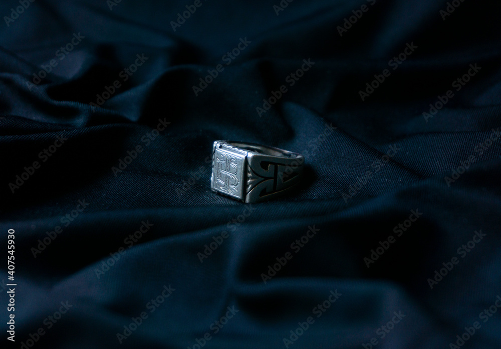 Silver ring with a dark fabric background, the ring has a background ...