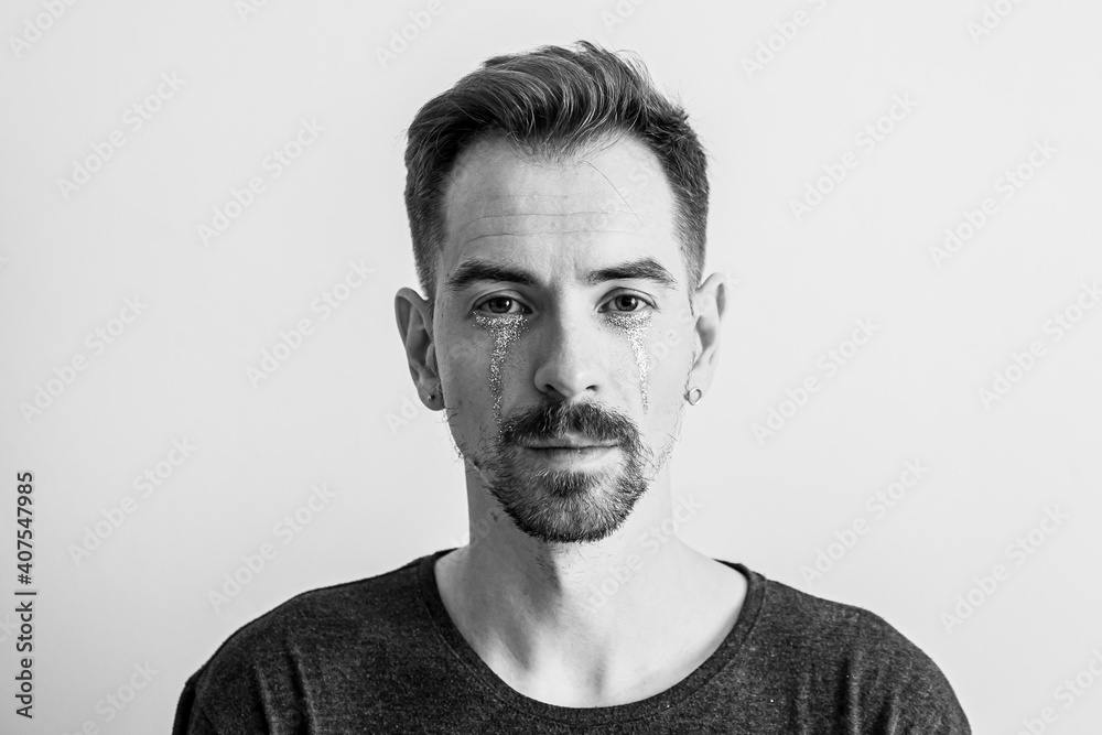 Sad man on a uniform background. Glitter in the form of tears on the ...