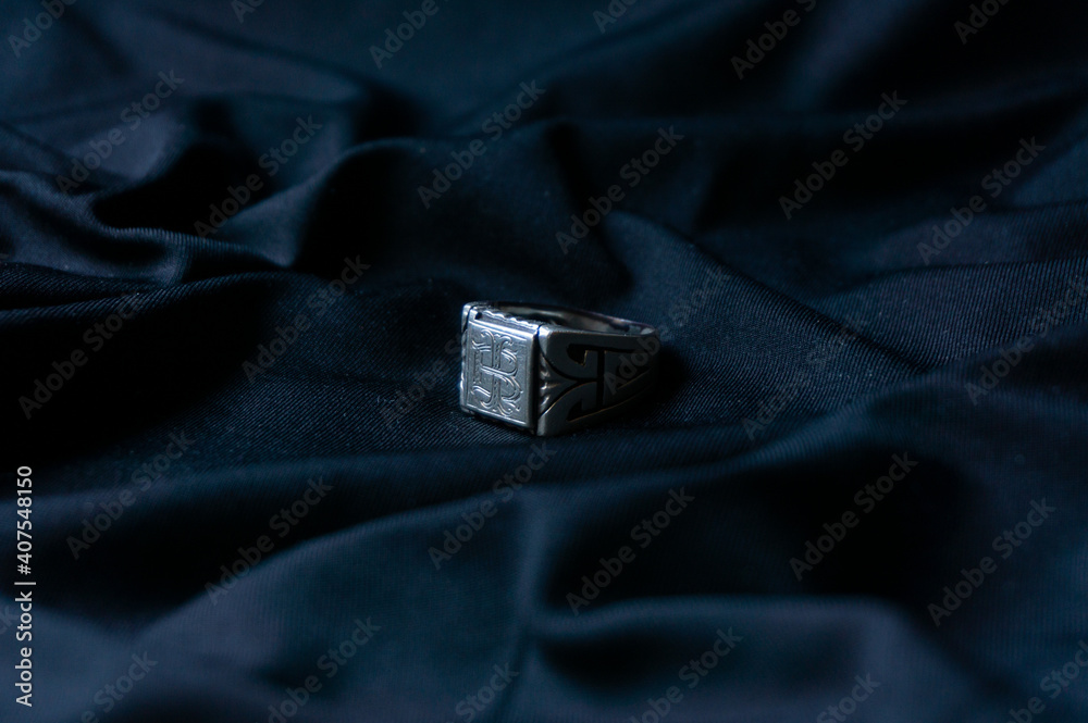 Silver ring with a dark fabric background, the ring has a background ...