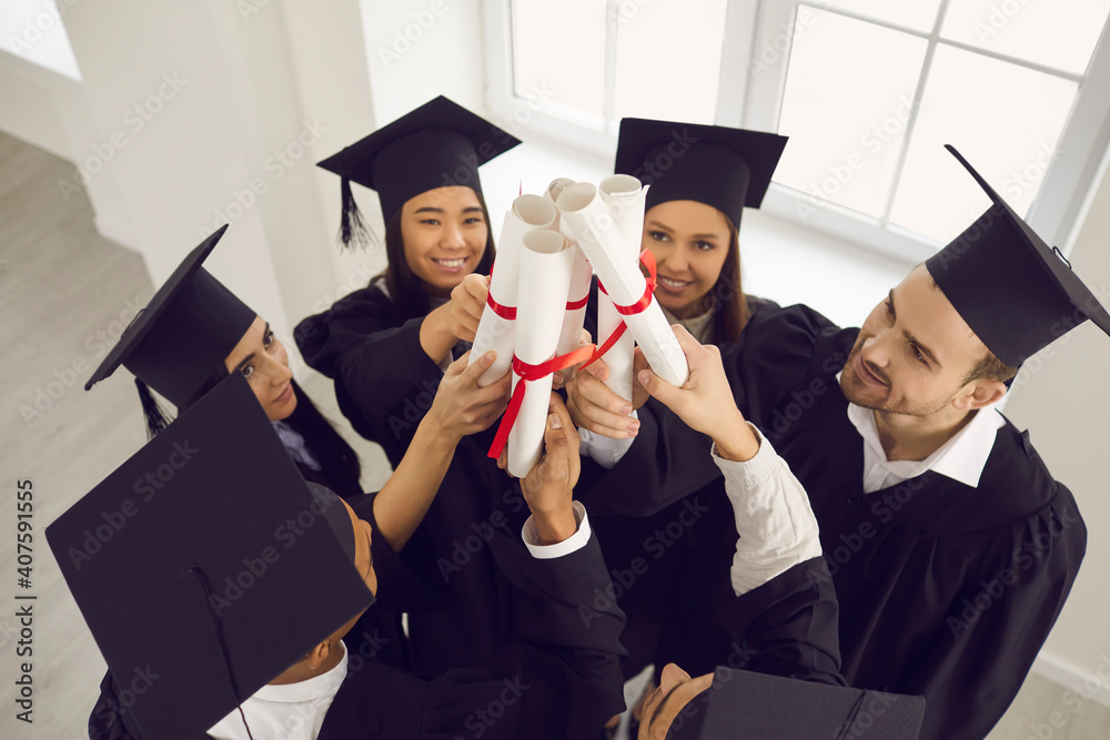 Top view at angle of happy graduates raising up their hands with ...