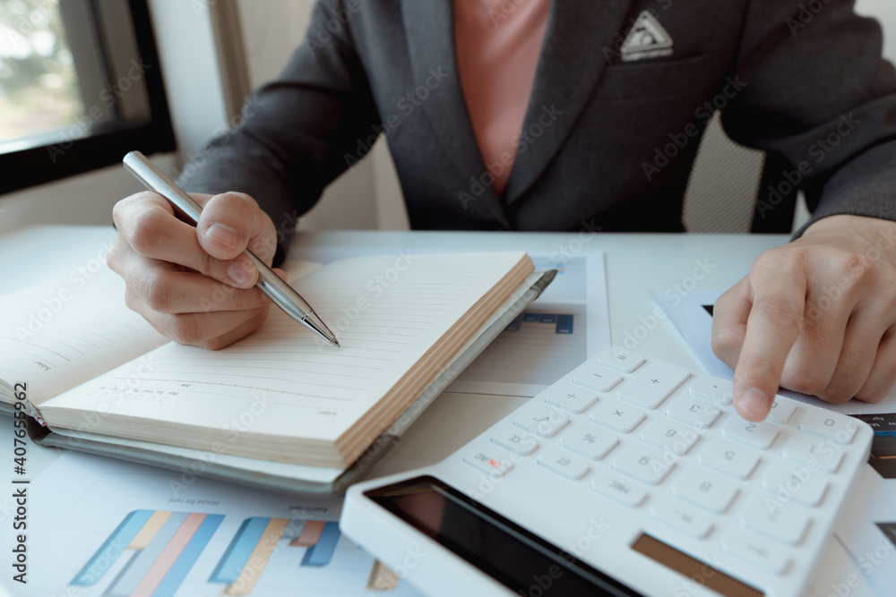 Business accountants are taking notes in notebooks and using a ...