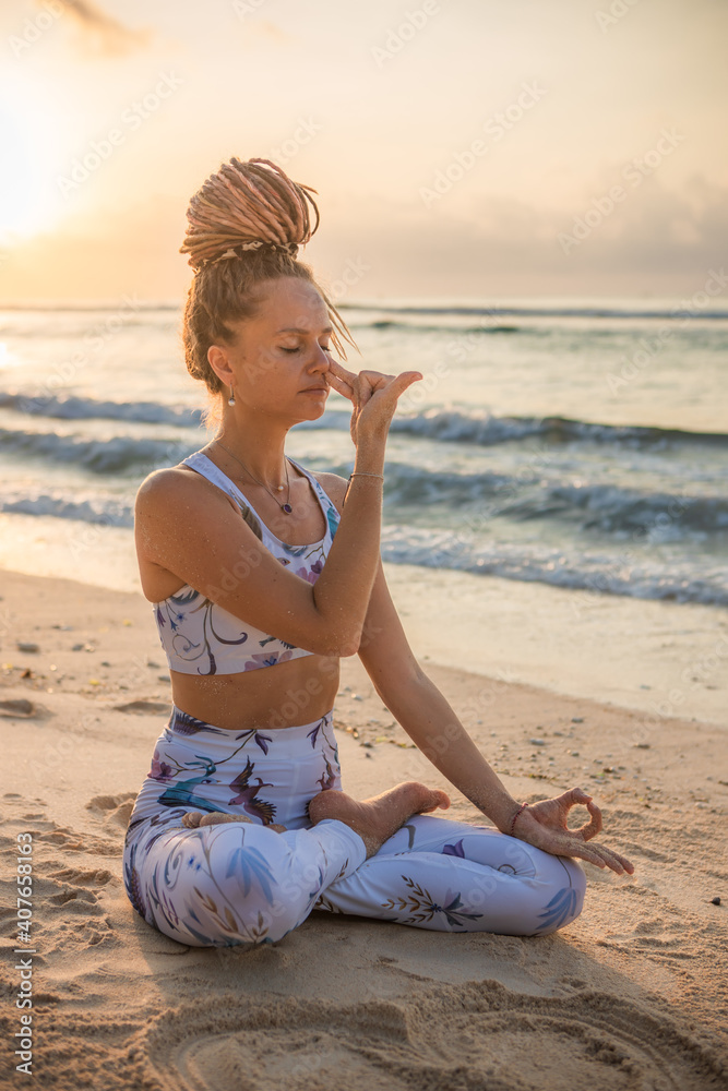 Yogi woman sitting in lotus pose, practicing Anuloma Viloma Pranayama, Alternate Nostril ...