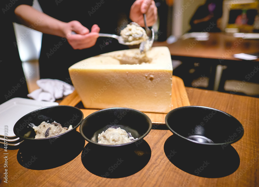 Woman serving a gourmet cheese preparation in black pottery in a wooden ...