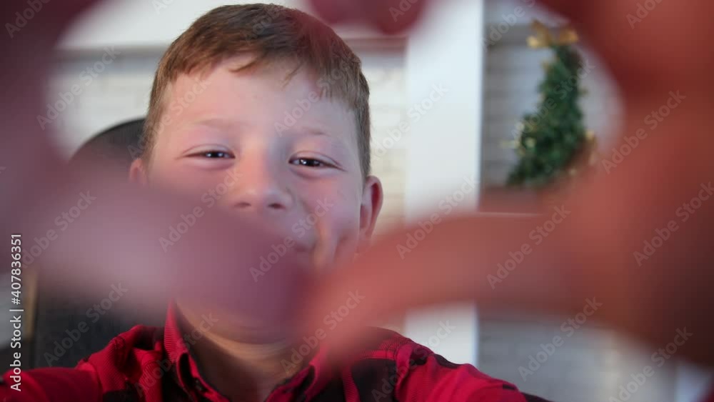 Portrait of happy boy with a heart shape made by hands. Lad shows the ...