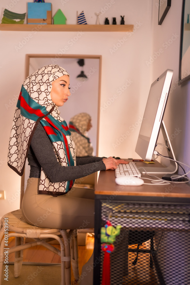 Arab girl with a white veil at her home computer, making a video call ...
