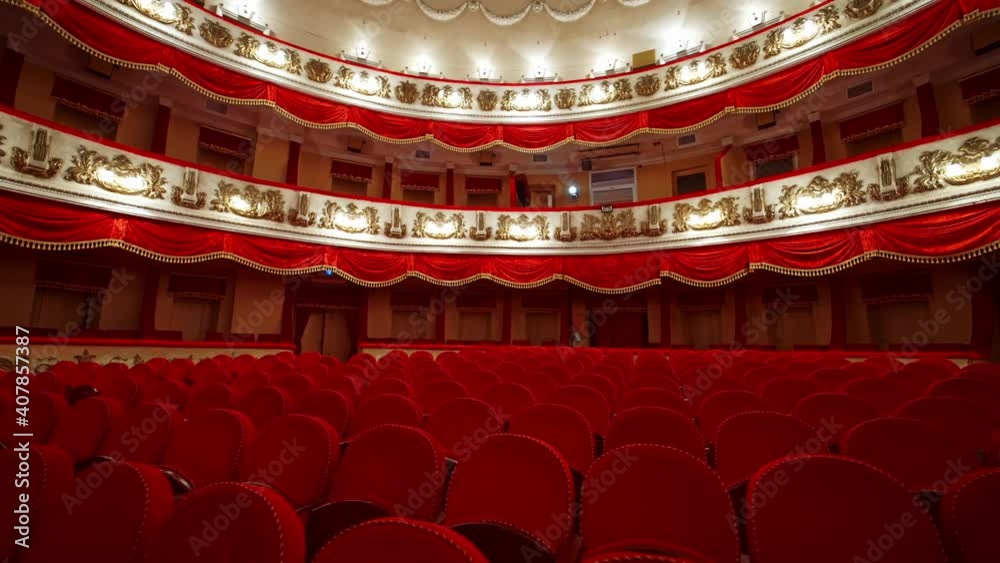 Interior of vivid red opera house. Rows of empty velvet seats and tiers ...