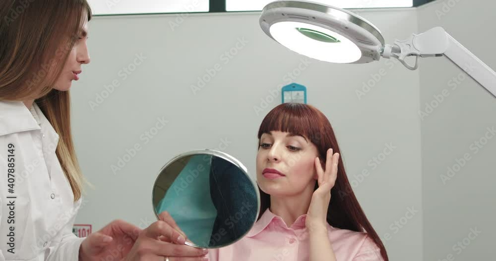 Plastic surgery. Young Beautiful Doctor Woman Shows Mirror To Patient ...