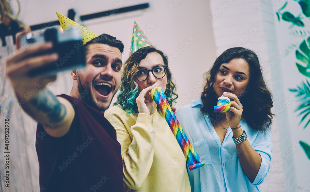Young women and man making common picture on camera blowing colourful ...