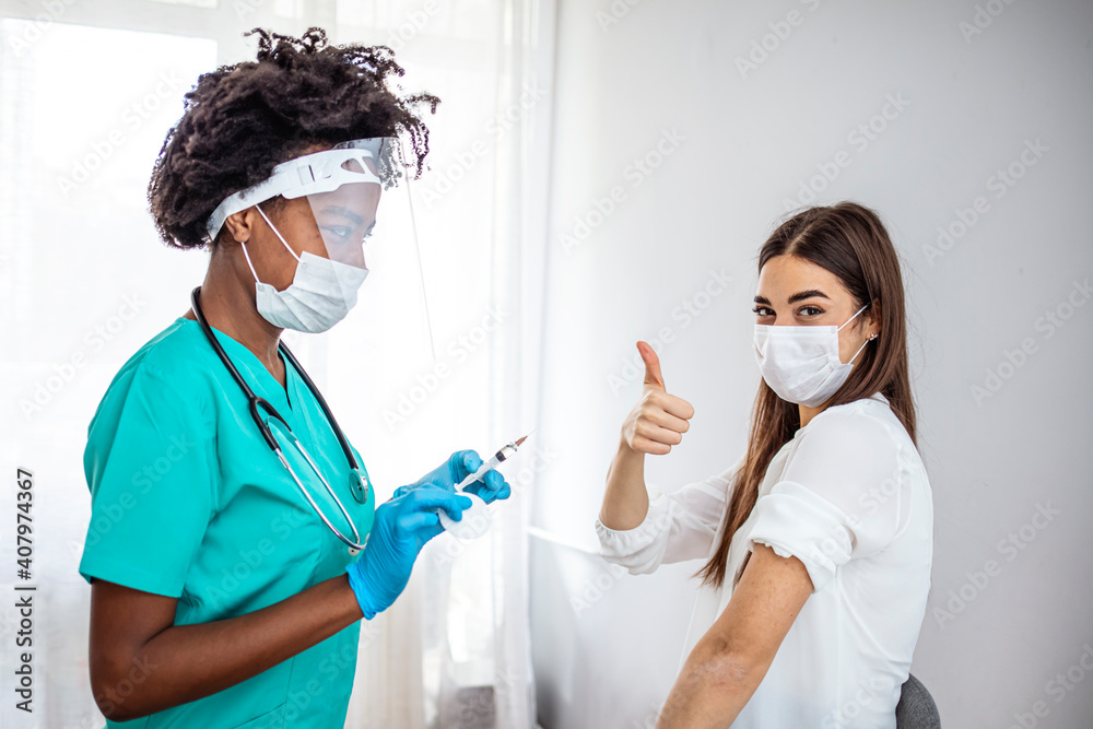 Young female doctor holding vial with COVID-19 vaccine while female ...